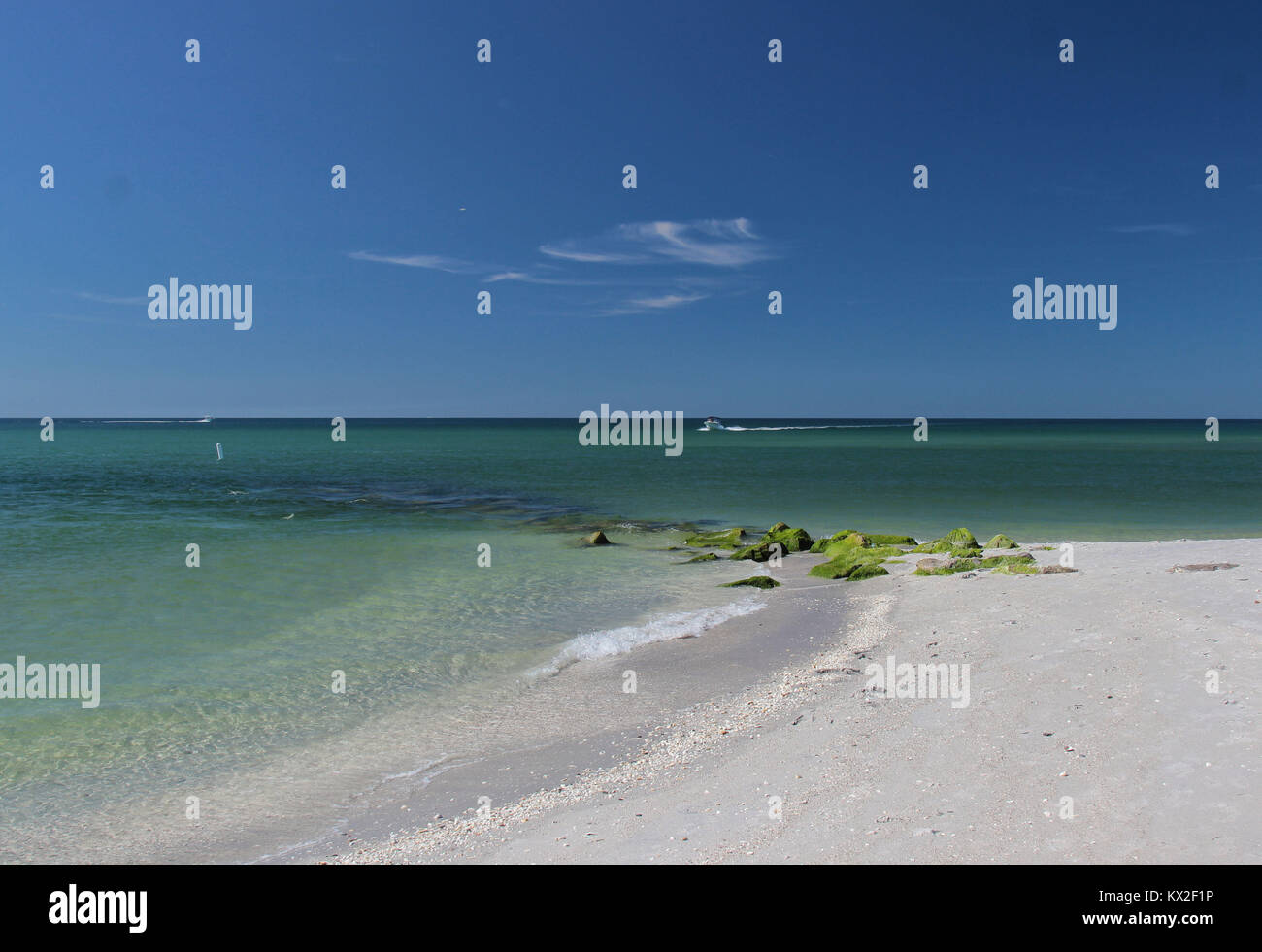 Landscape of a rocky and sandy beach with boat cruising past at Stump ...