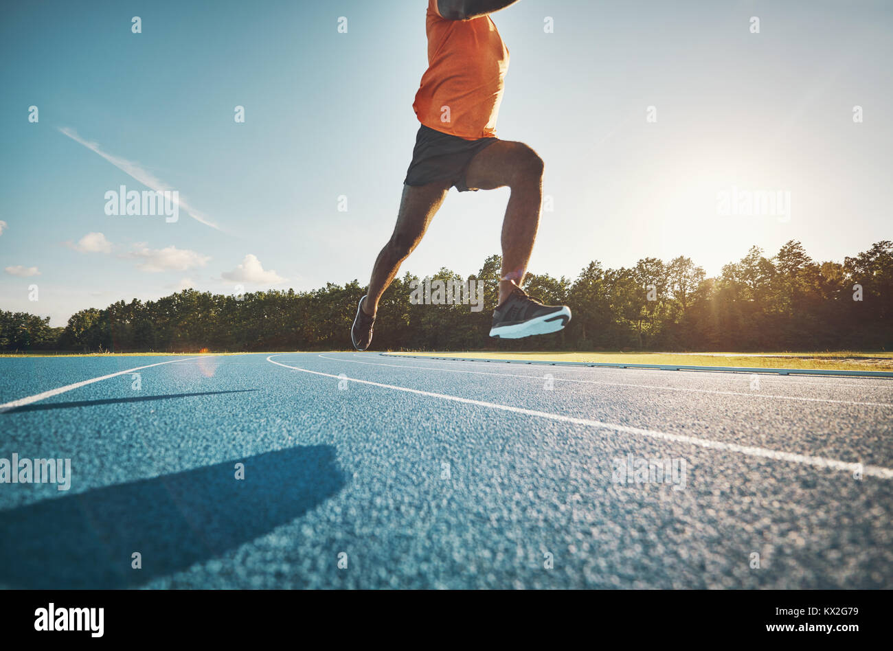 Fit young African male athlete in mid air while sprinting alone down a ...