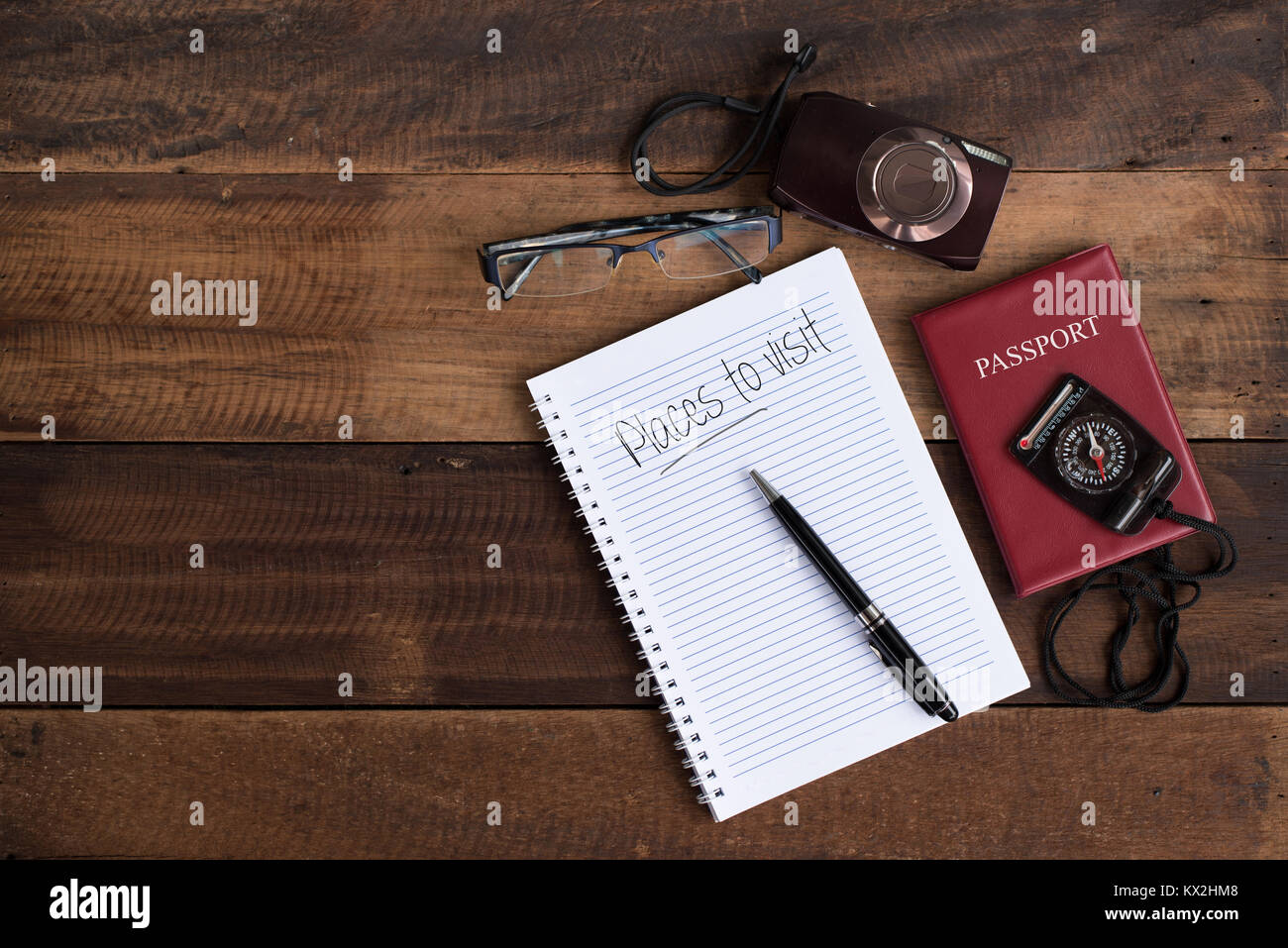 notebook, camera, compass, spectacles and passport on wooden table with ...