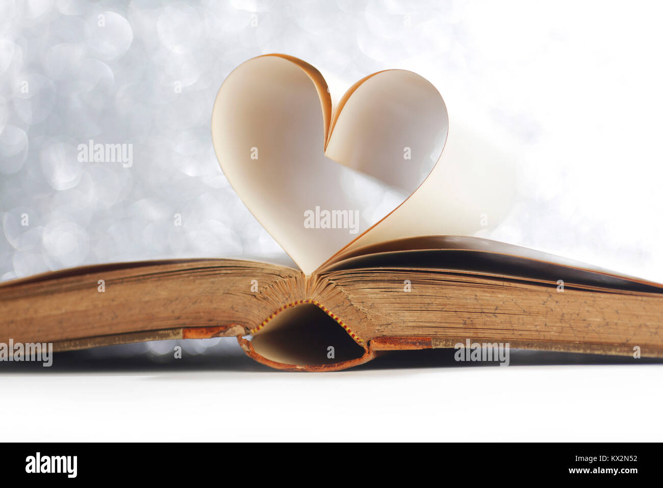 Pages of open book rolled in heart shape on glitter background Stock ...