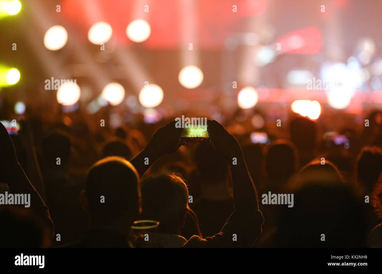 many people and man taking smart phone at live concert and lights on ...