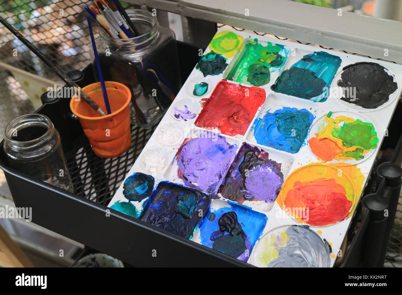 Modern style art palette with multi-color paints on a black tool cart ...