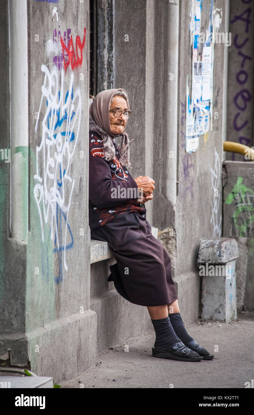 Local lifestyle: poor old woman sits on a window ledge with graffiti ...