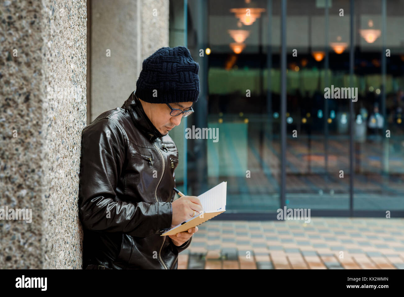 An Asian Man in a Brown Jacket with a Small Notebook in His Hands Stock ...