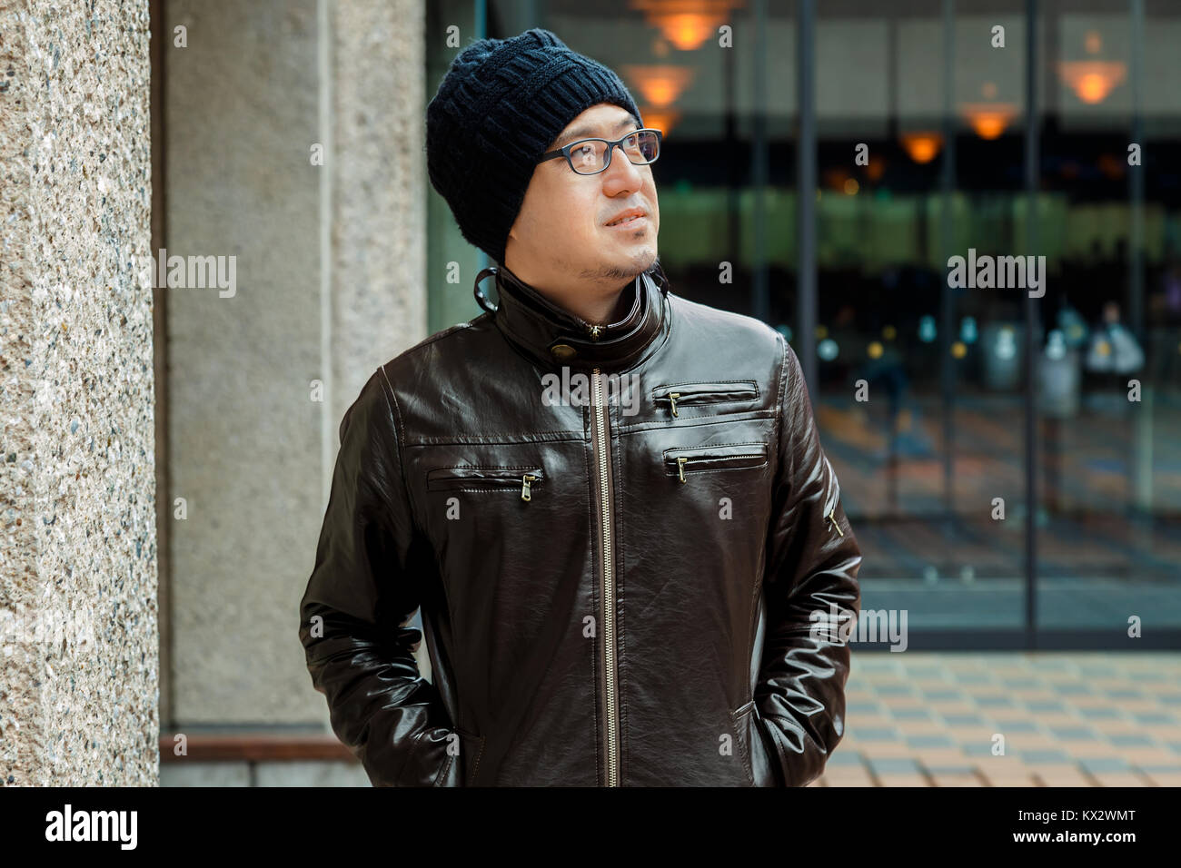 An Asian Man in a Brown Jacket is Strolling a Street Stock Photo - Alamy