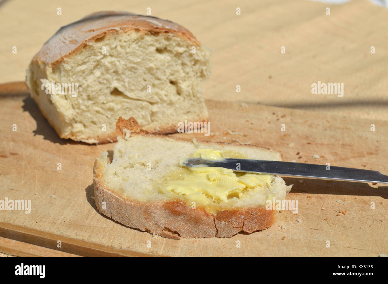 Piece of delicious just made domestic bread with butter on wooden ...