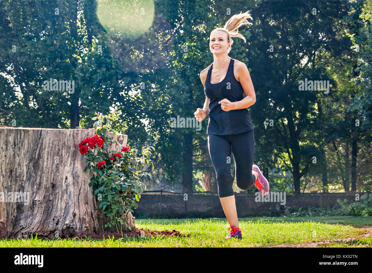 Blonde young woman running in the park Stock Photo - Alamy