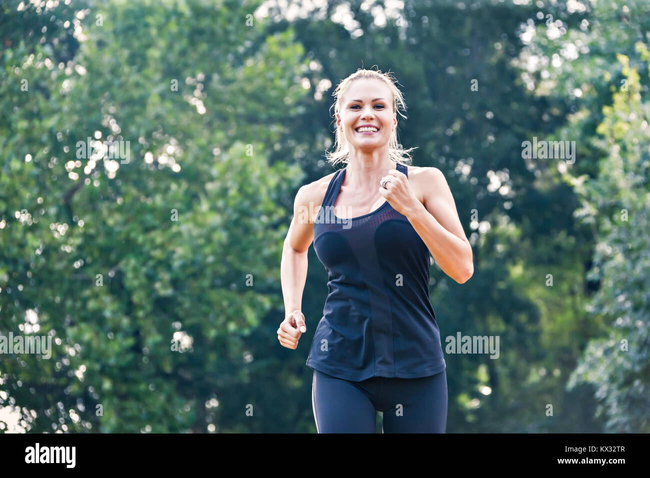 Blonde young woman running in the park Stock Photo - Alamy