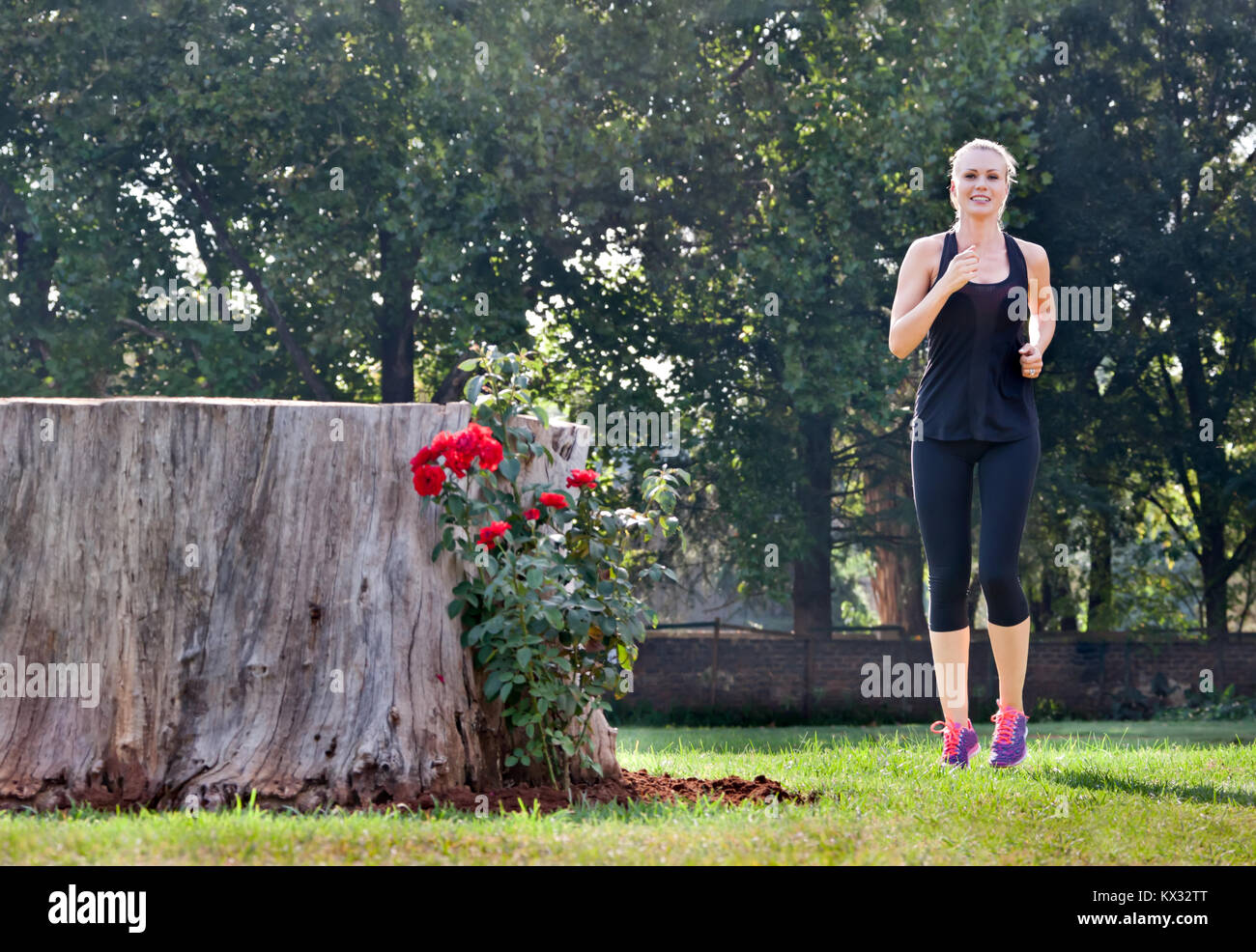 Blonde young woman running in the park Stock Photo - Alamy