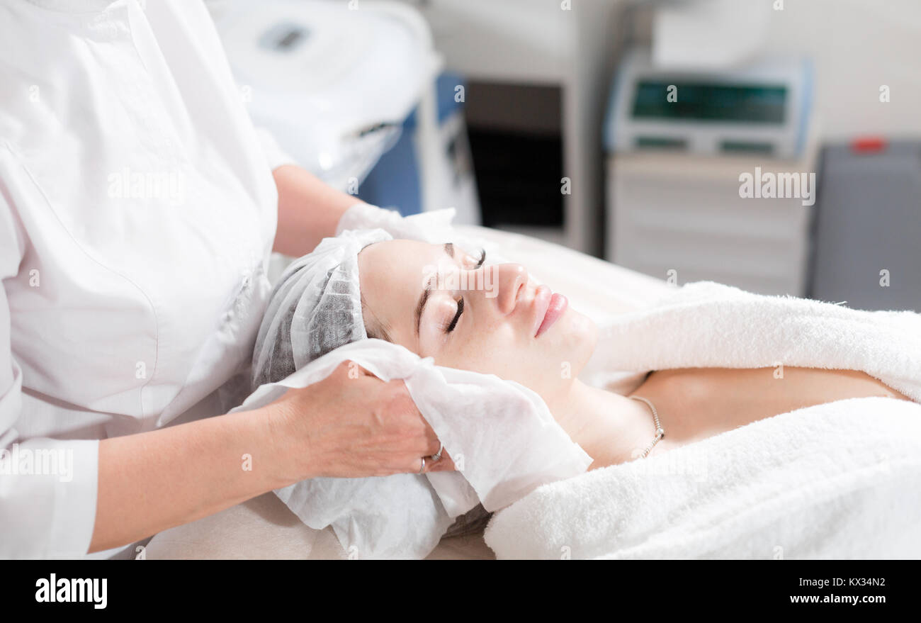 Wipe with sterile napkin face. Young pretty woman receiving treatments ...