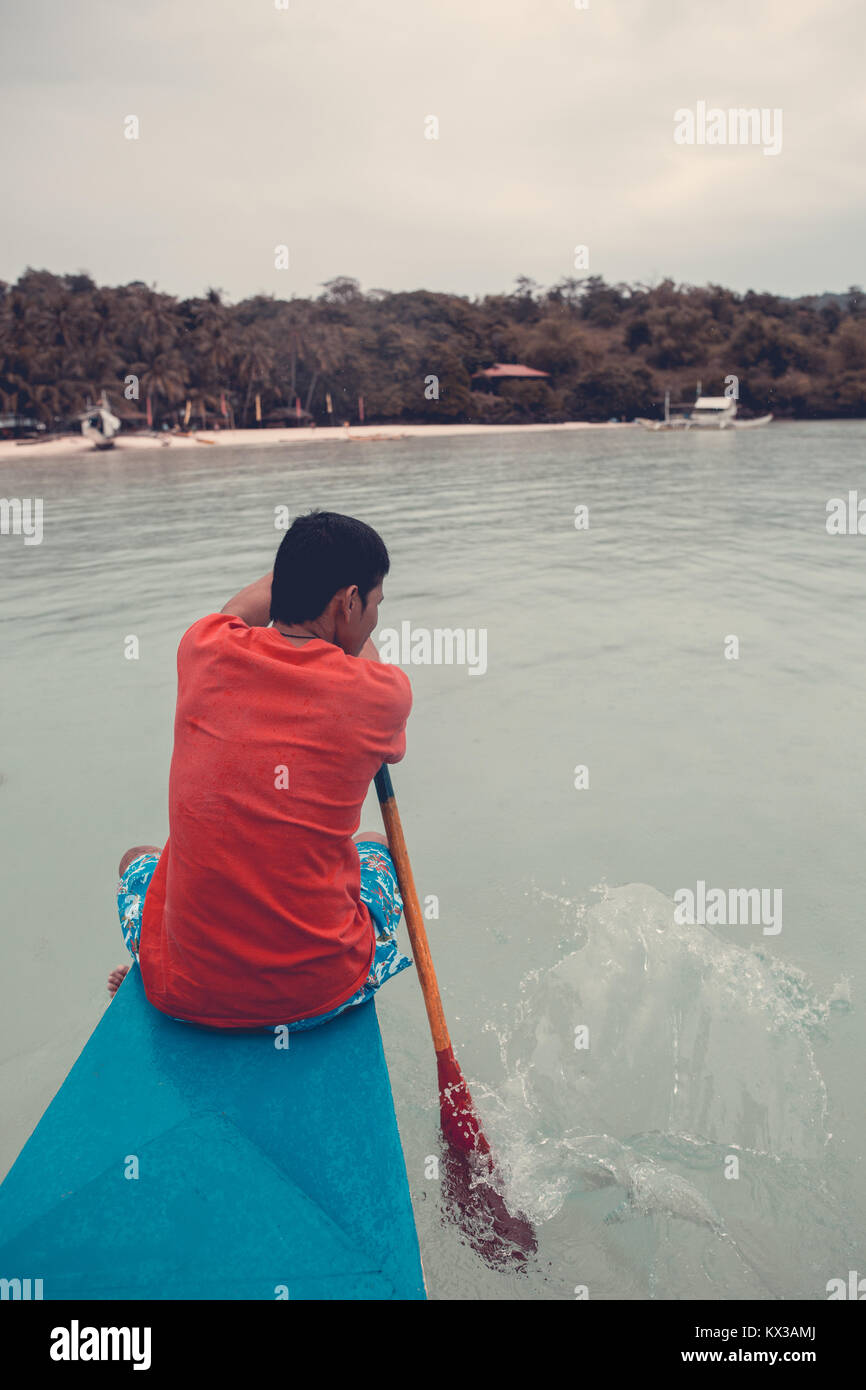 Man rowing a boat to an island in the Philippines Stock Photo - Alamy