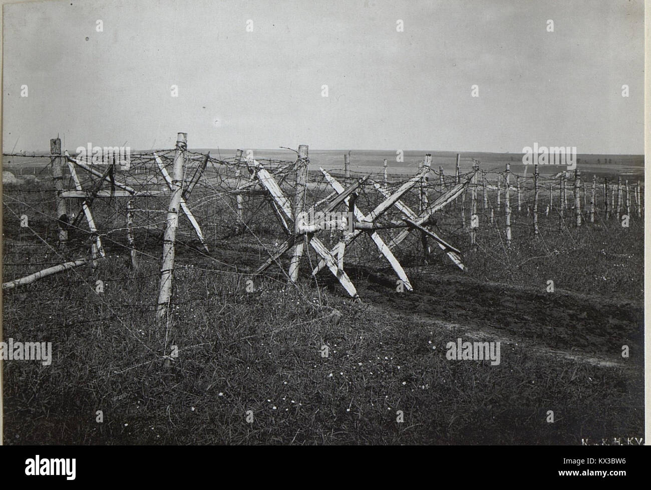 This image depicts a barbed-wire fence with lower wooden posts ...