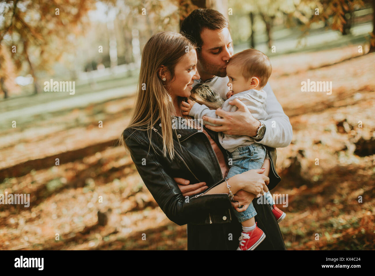 Happy young parents have fun with baby boy in autumn park Stock Photo ...