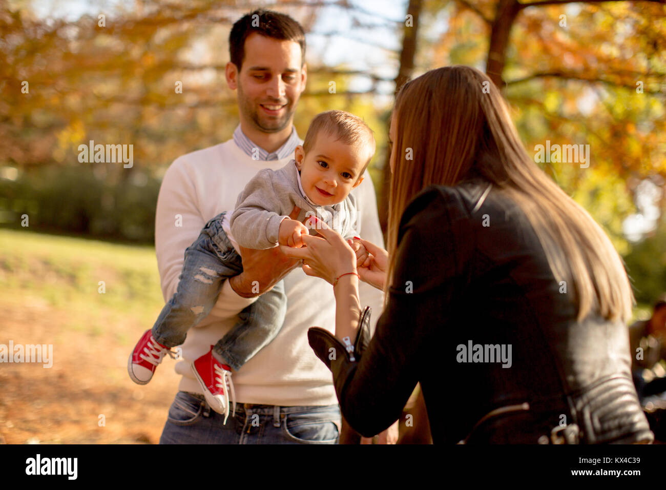Happy young parents have fun with baby boy in autumn park Stock Photo ...