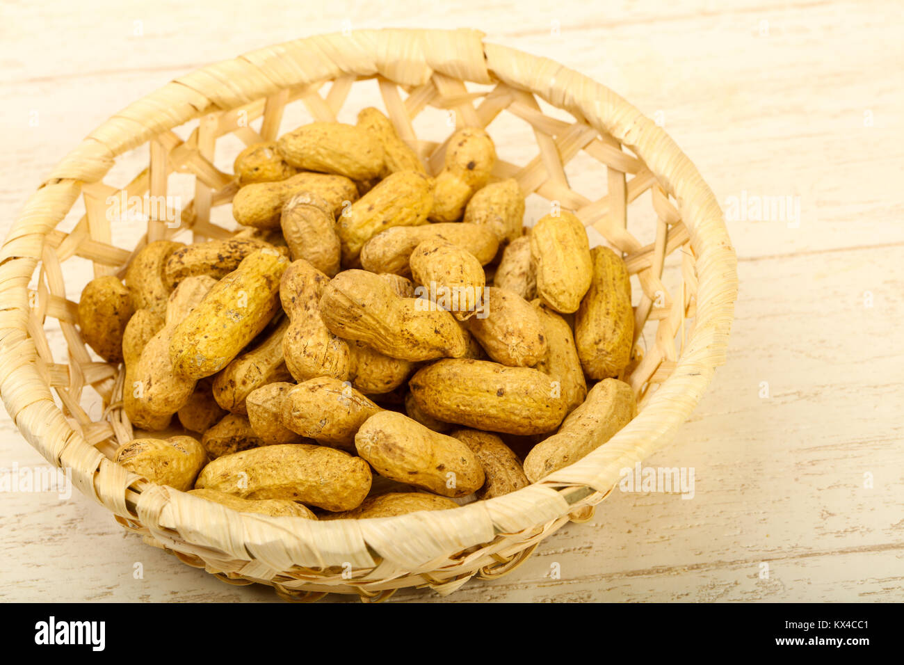 Unpeeled peanuts heap in the basket over wooden baclground Stock Photo ...