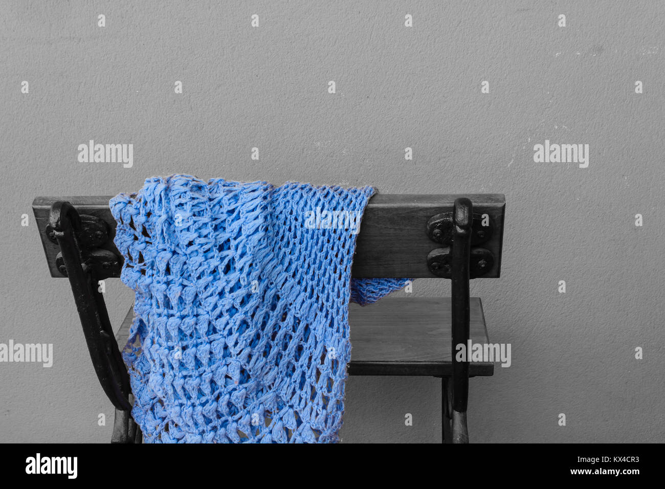a wooden bench with with a woolen shawl blue abandoned on the back /a ...