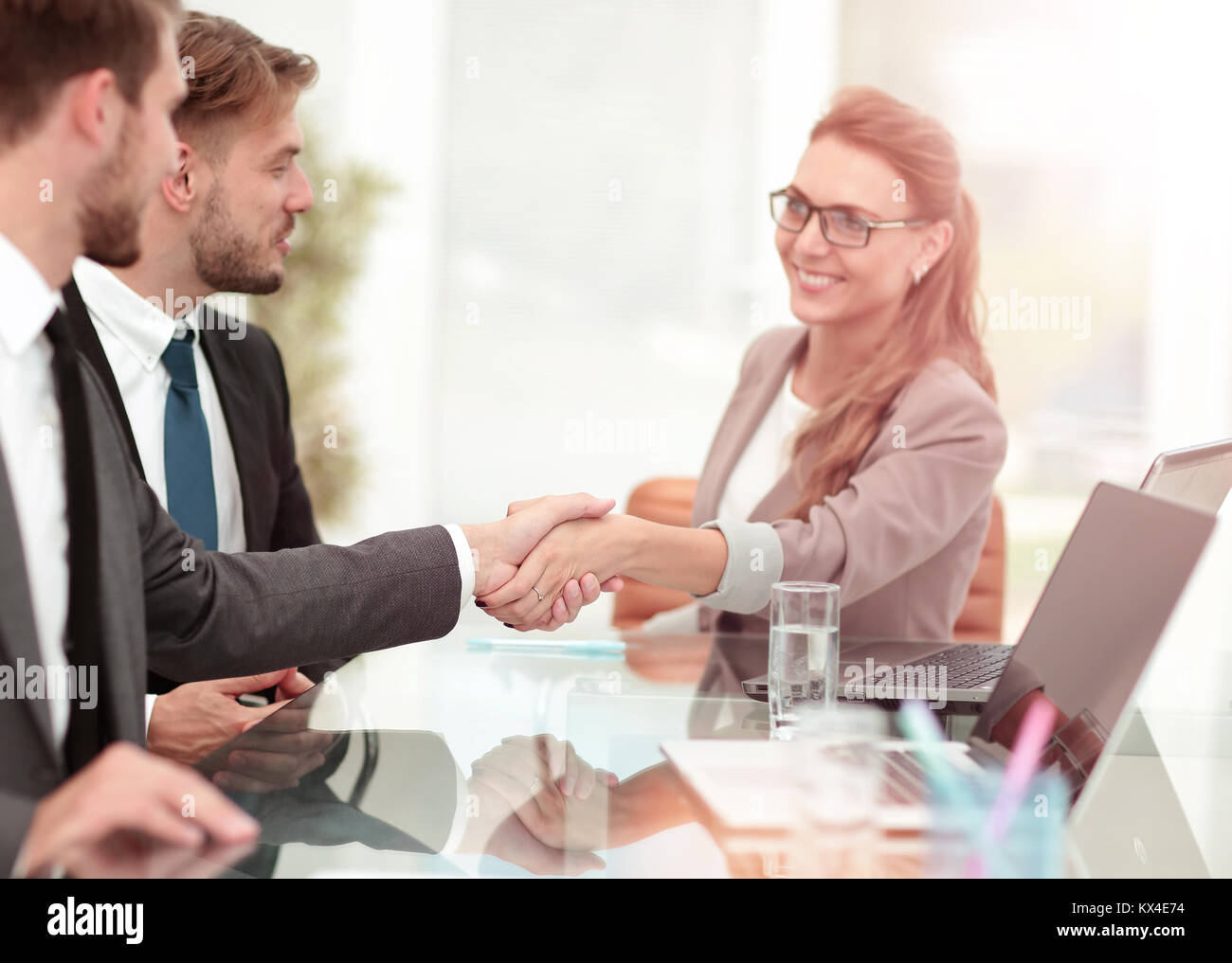 Happy business partners shaking hands in an office Stock Photo - Alamy