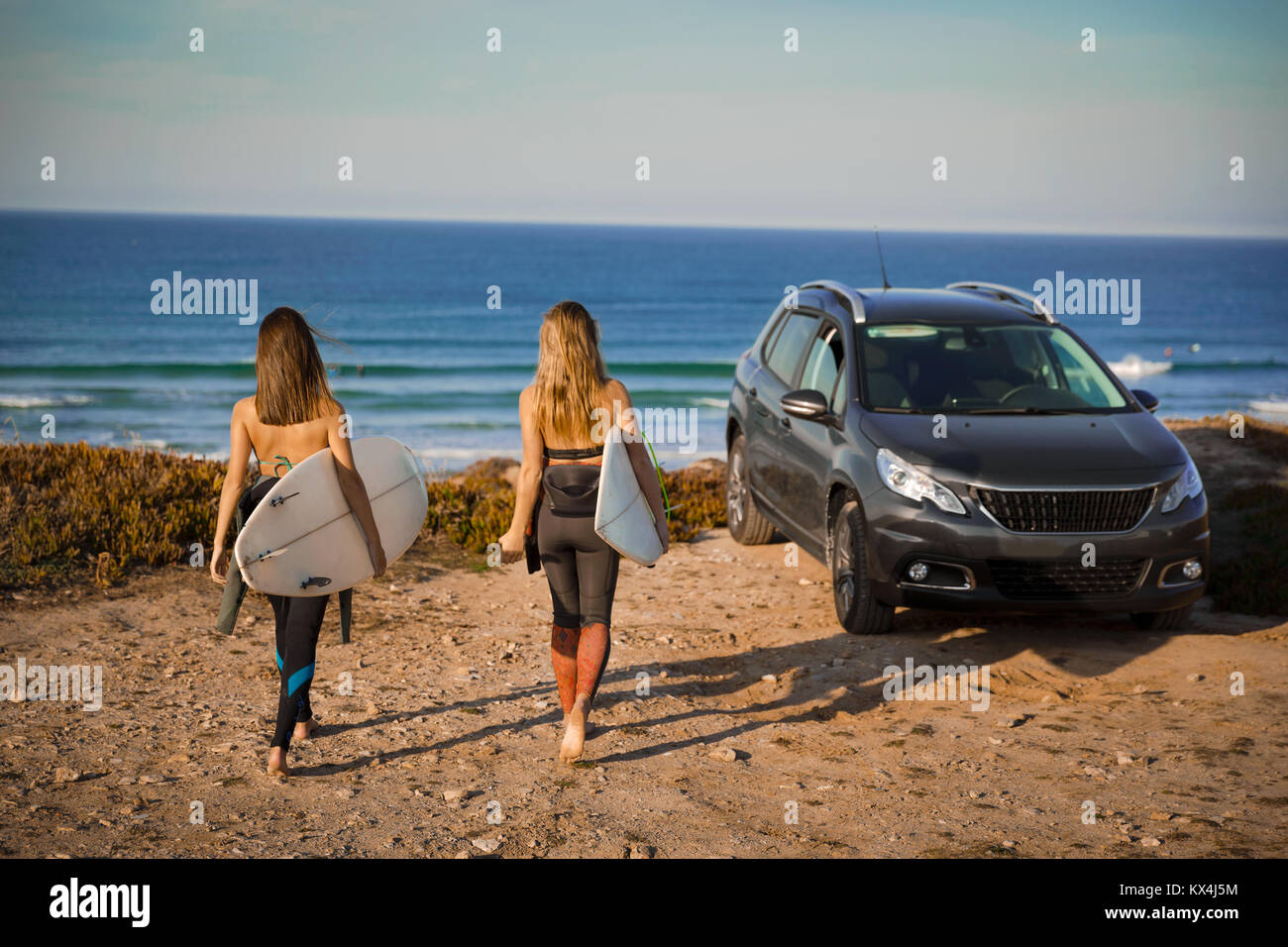 Two beautiful surfer girls near the coastline with her car, and getting ...