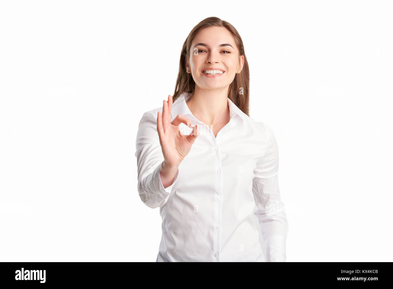 Beautiful young woman gesturing okay sign while standing at isolated ...