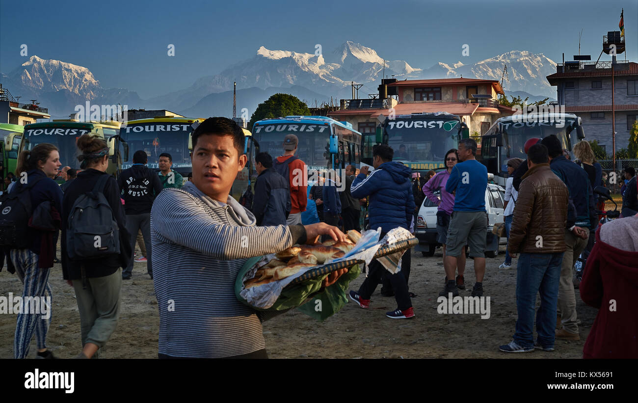 Nepali seller at tourist bus stop in front of Annapurna massif, Pokhara ...