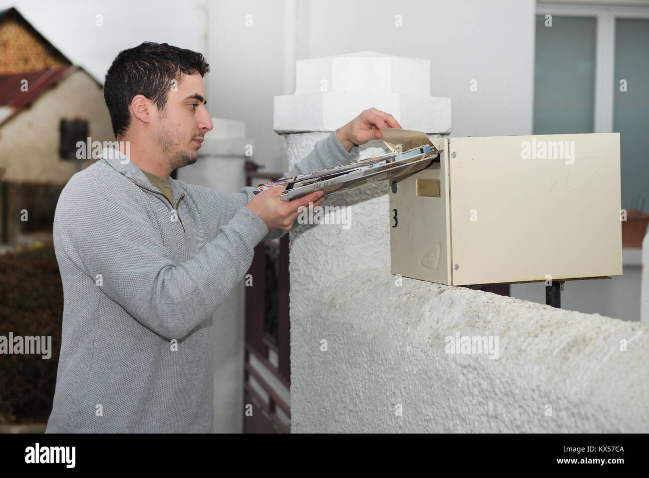 young man putting newspaper from the mailbox Stock Photo - Alamy