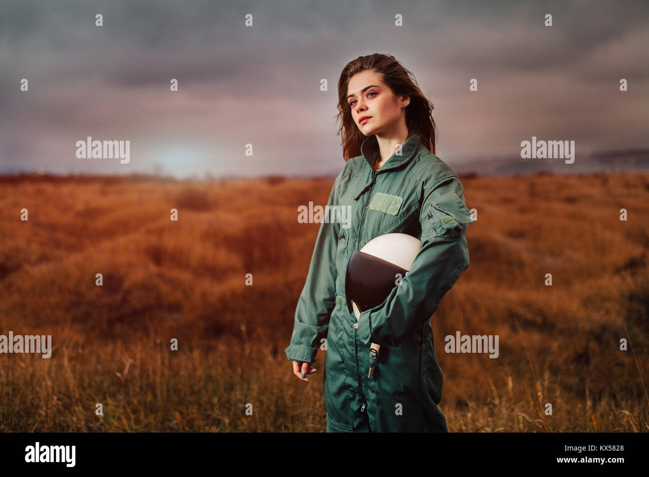 portrait of young beautiful girl pilot in uniform in the sunset field ...