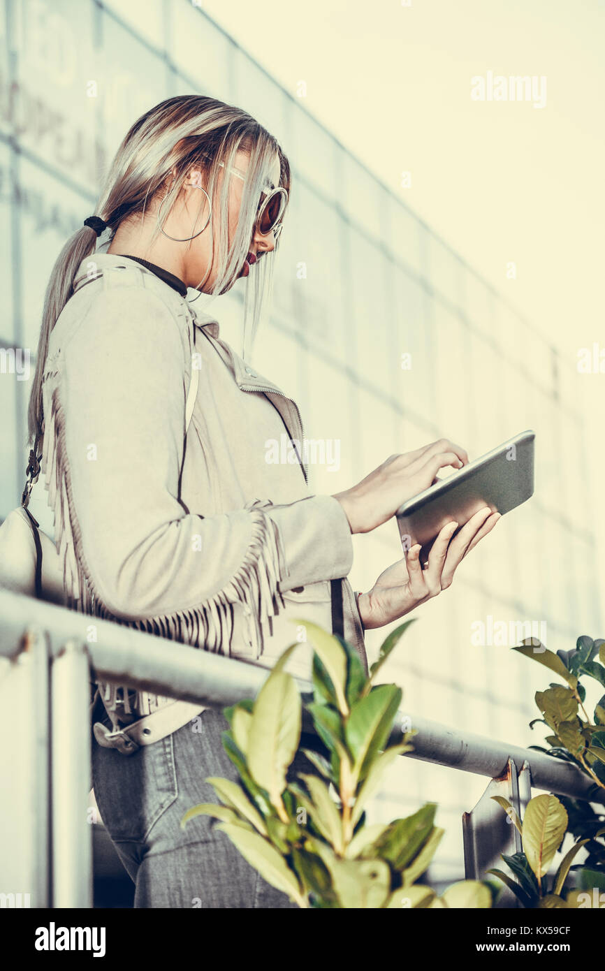 Modern and urban woman standing outdoors and using a tablet. Using ...
