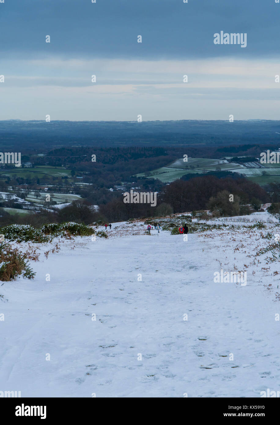 Snow covered footpath with walkers leading from Hergest Ridge down into ...