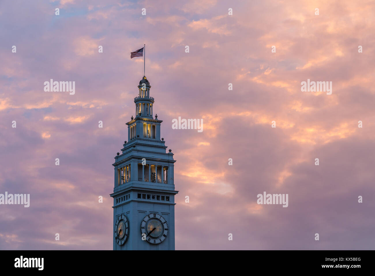Clouds reflect the sunrise behind the clock tower of the San Francisco ...
