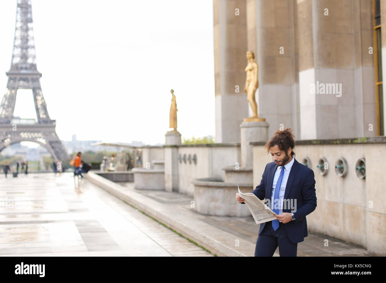 Mulatto pressman reading newspaper article near Eiffel Tower Stock ...