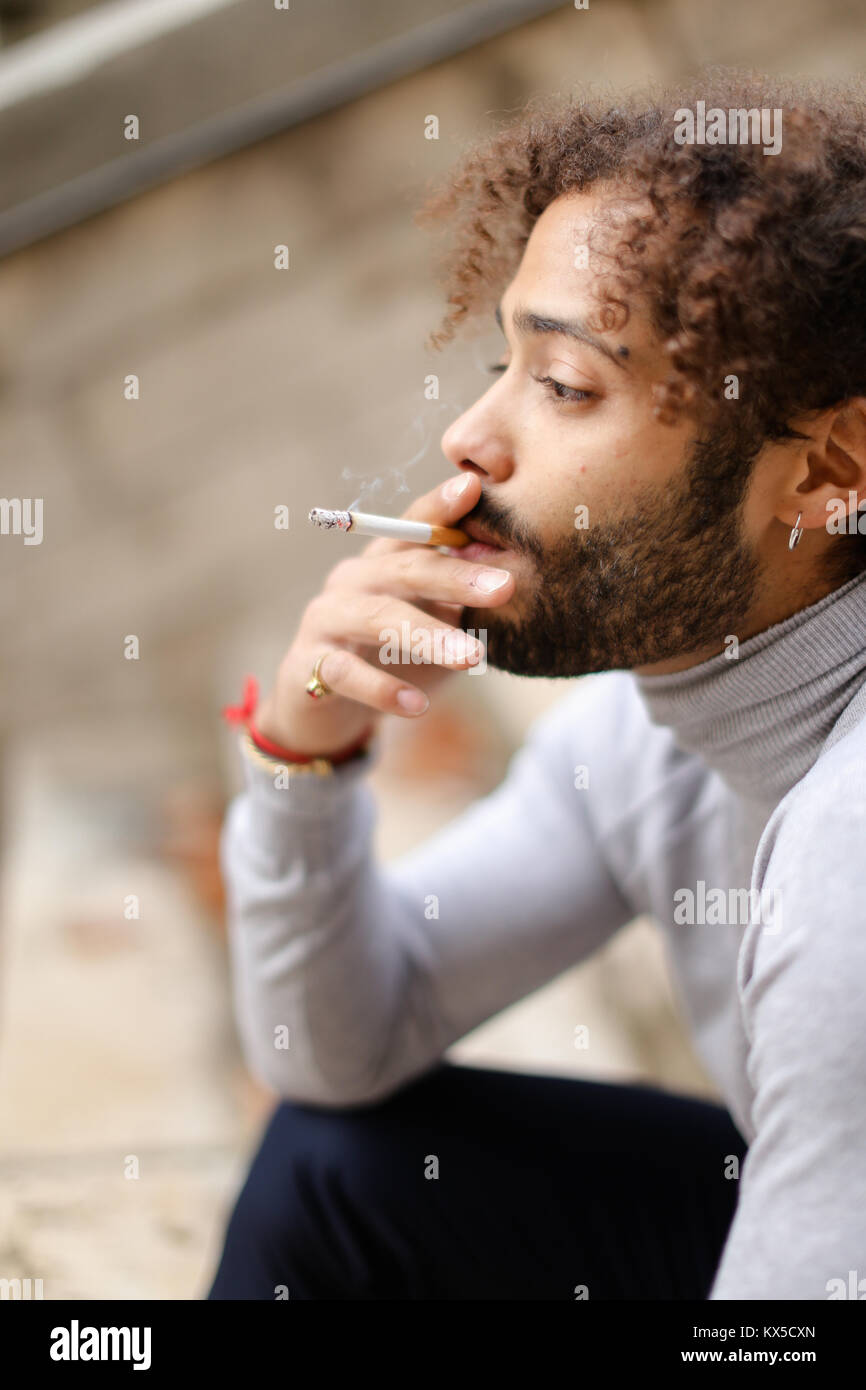Sad mix blood man smoking on steps Stock Photo - Alamy