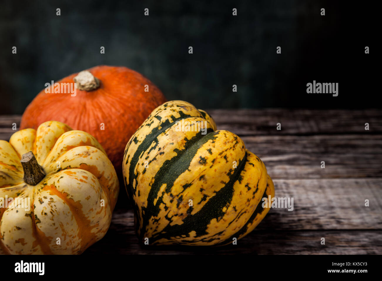 Three colourful various squash on wooden table with dark background ...