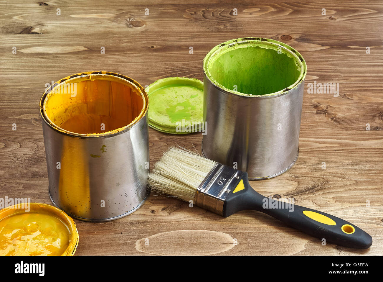 green and yellow paint cans with a brush on a rustic wooden background ...