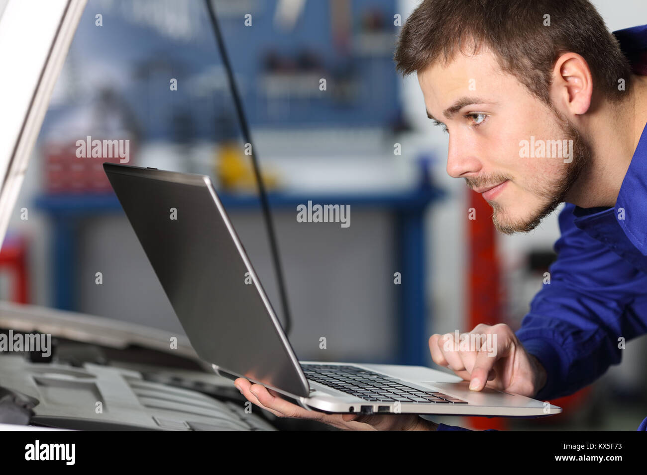 Side view portrait of a mar car mechanic checking electronic components ...