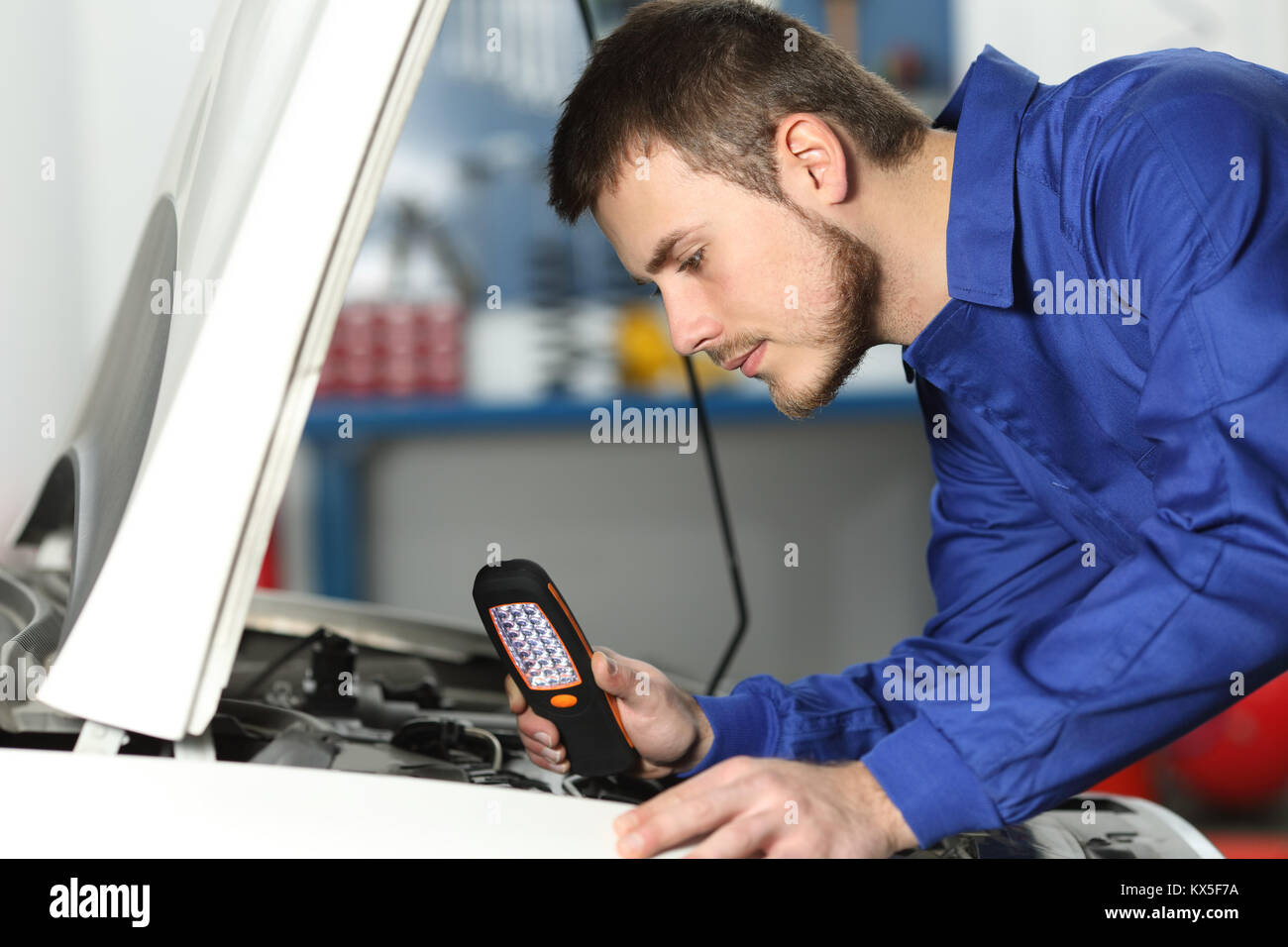 Side view of a car mechanic checking engine for failures in a ...