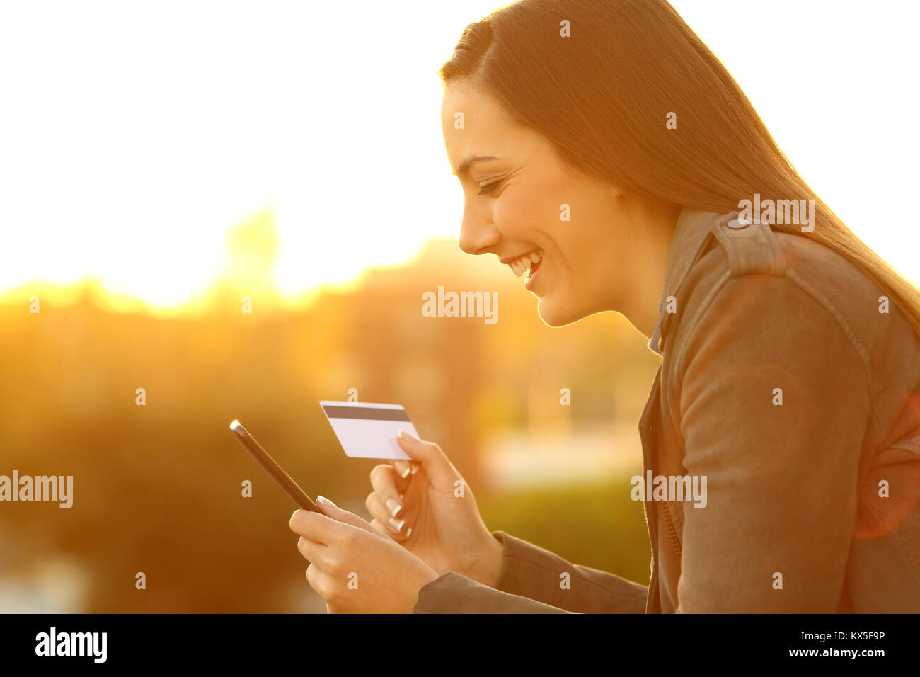 Side view portrait of a smiley girl buying on line with credit card and ...