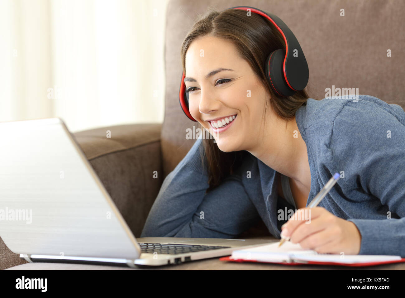 Happy girl learning on line listening audio tutorials with headphones ...