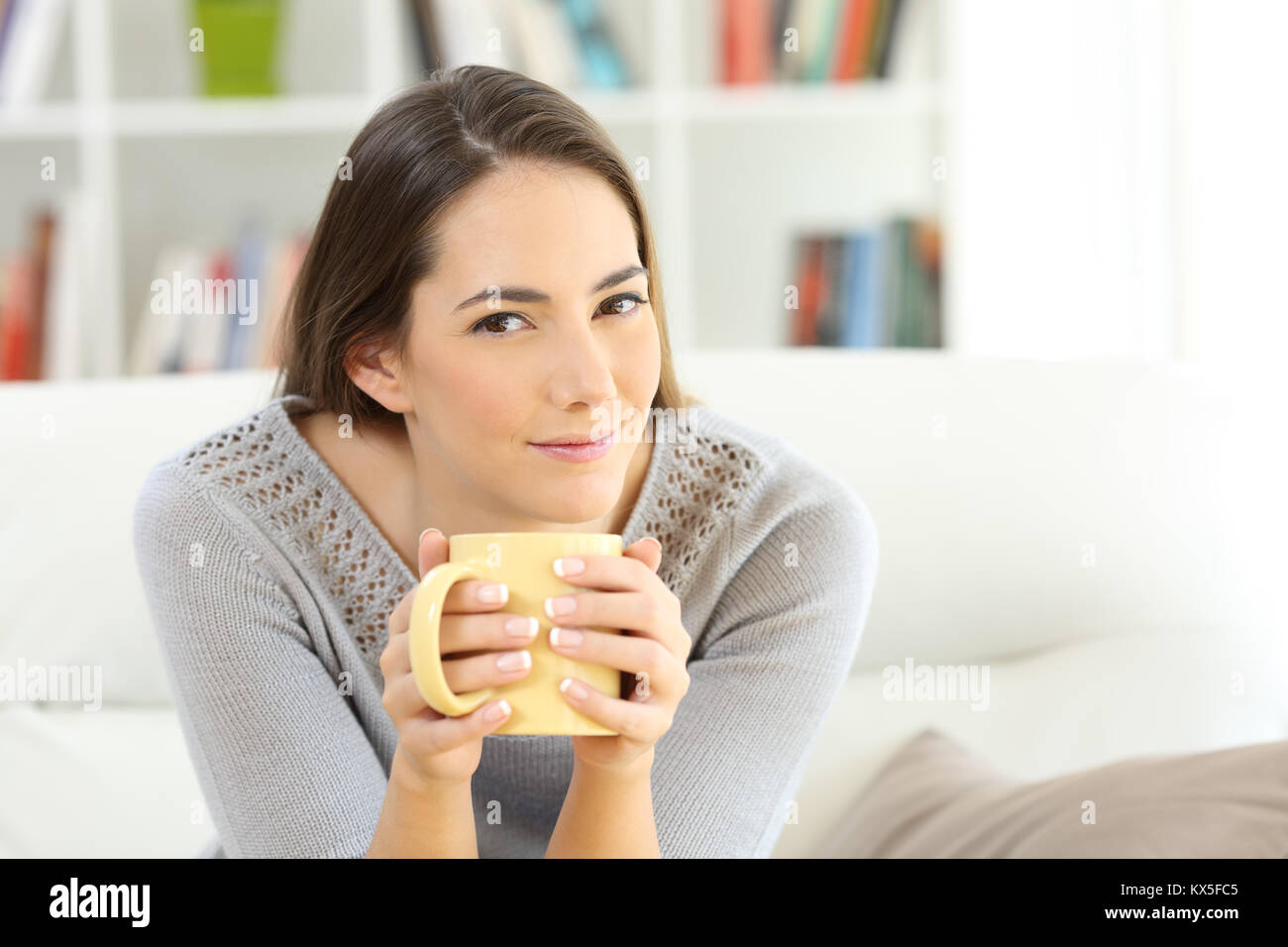 Portrait of a housewife looking at camera holding a coffee cup sitting ...