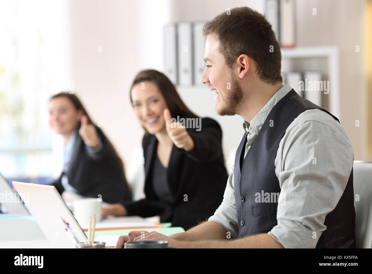 Proud employee receiving congratulations from his colleagues at office ...