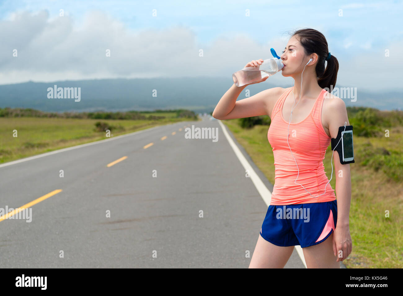 attractive young runner woman drinking water on road when she finished ...