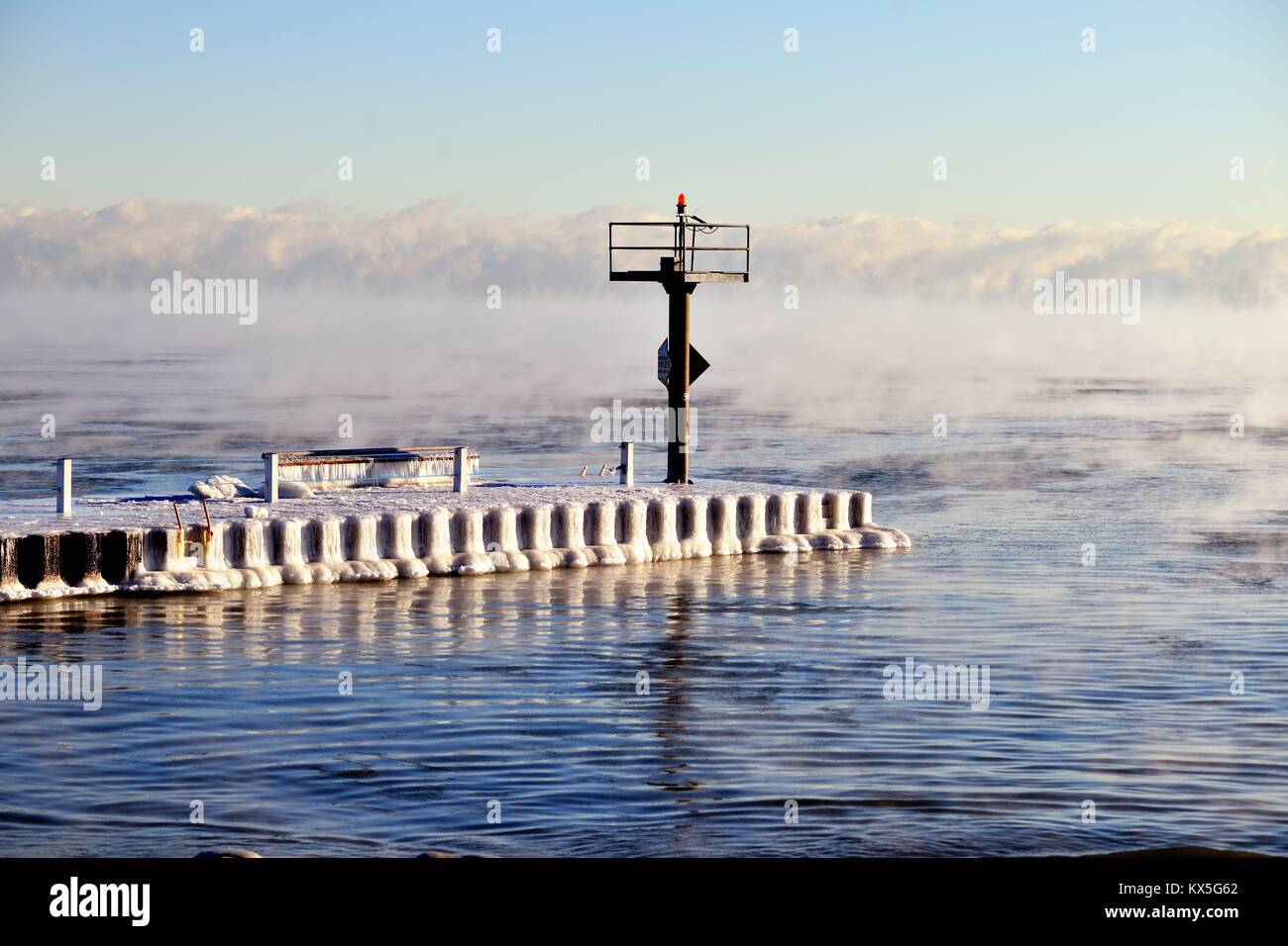 Ice forms on a breakwater as vapor rises from the Lake Michigan waters ...