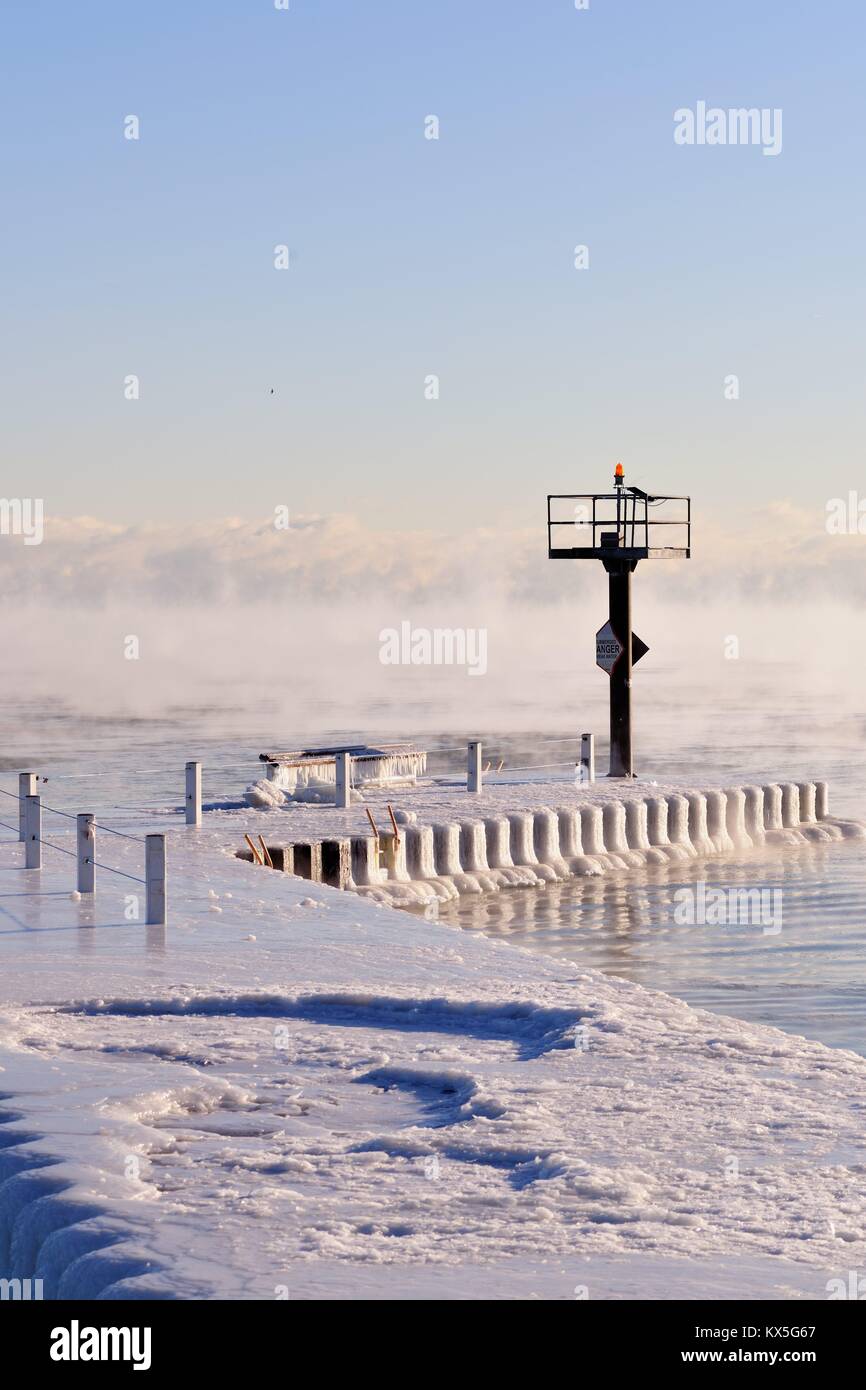 Ice coats on a breakwater as vapor rises from the Lake Michigan waters ...
