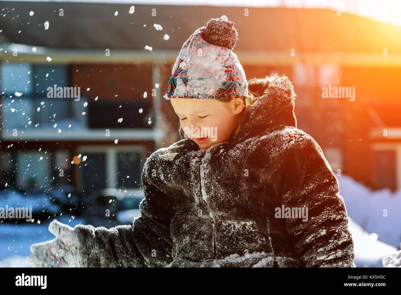 Happy little girl in white mittens walking in the winter park throws up ...