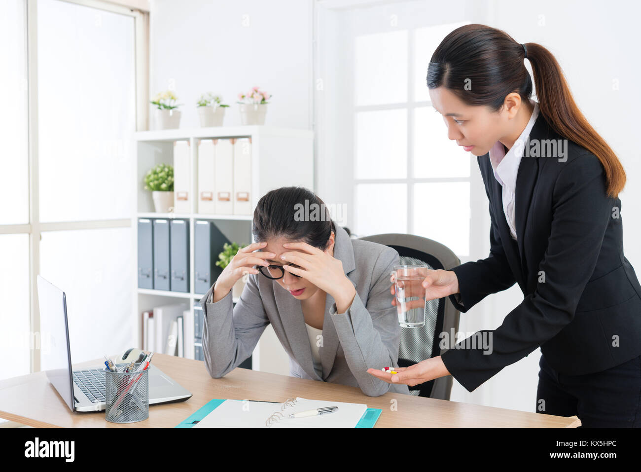 female company boss feeling headache in office and young employee girl ...