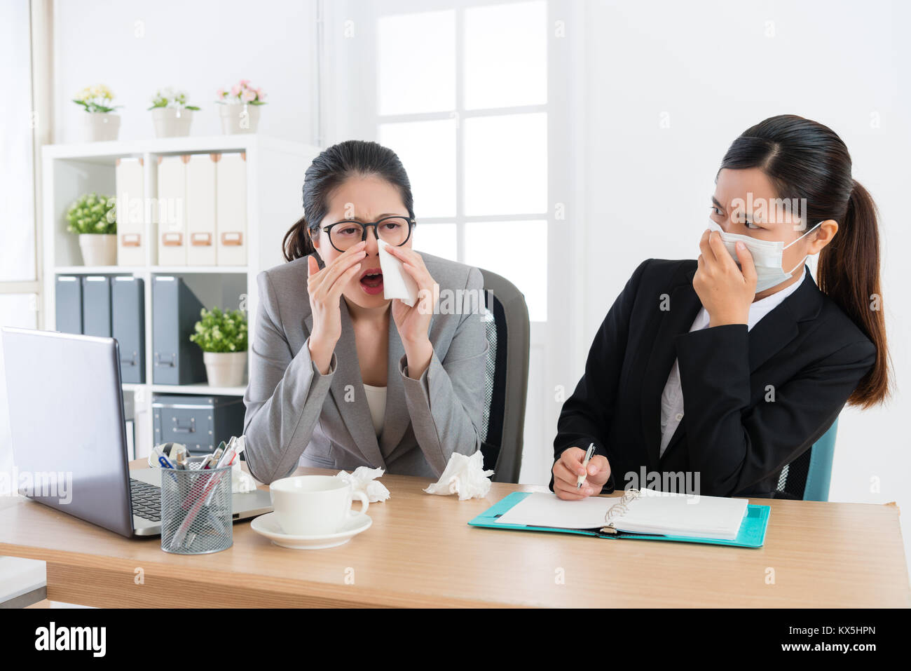 office worker woman sneezing during conference time and her colleague ...
