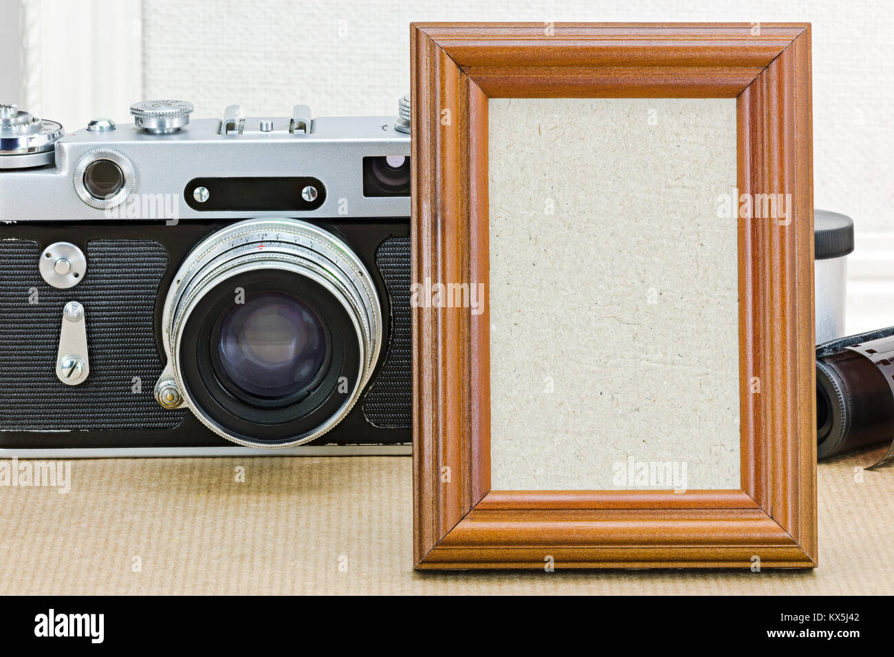 old retro camera and empty wooden photo frame on brown paper background ...