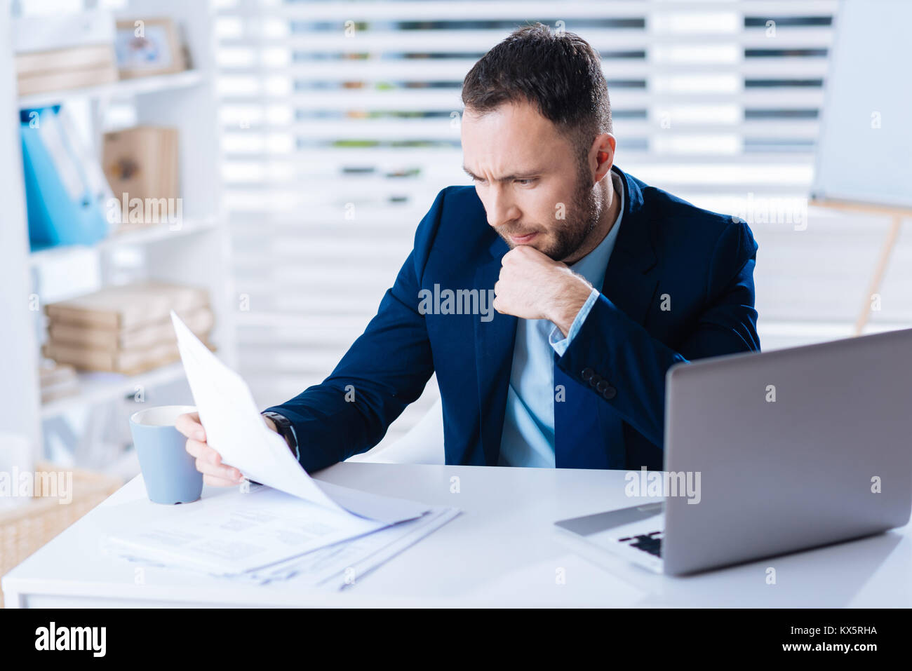 Busy young manager looking concentrated while reading the documents ...