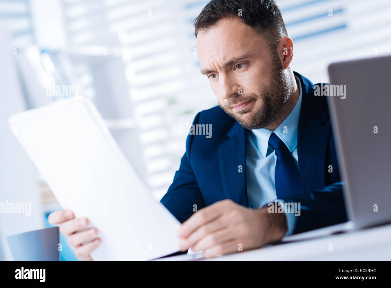 Upset manager looking unhappy while reading the documents Stock Photo ...