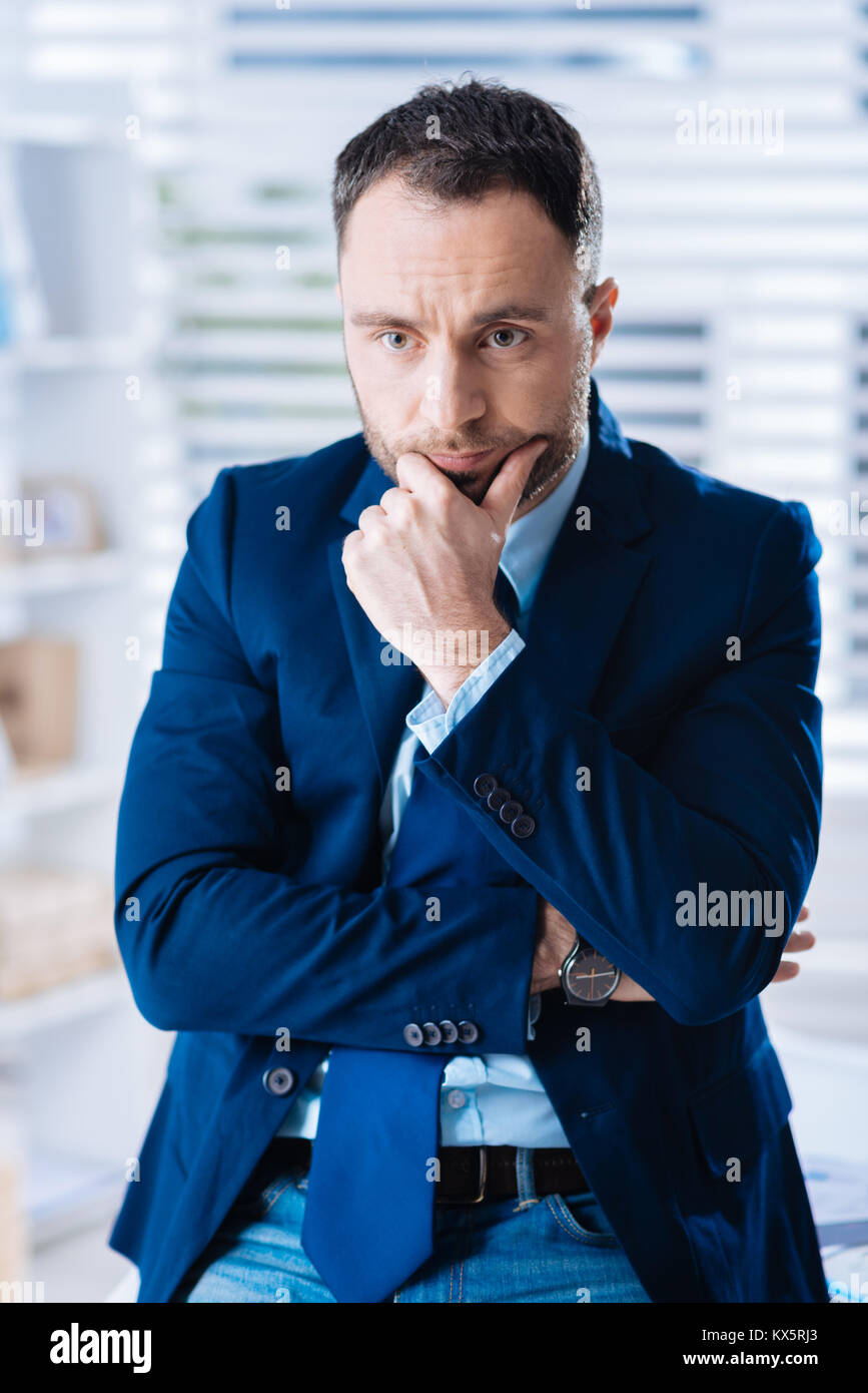 Smart calm businessman touching his face while thinking about the ...