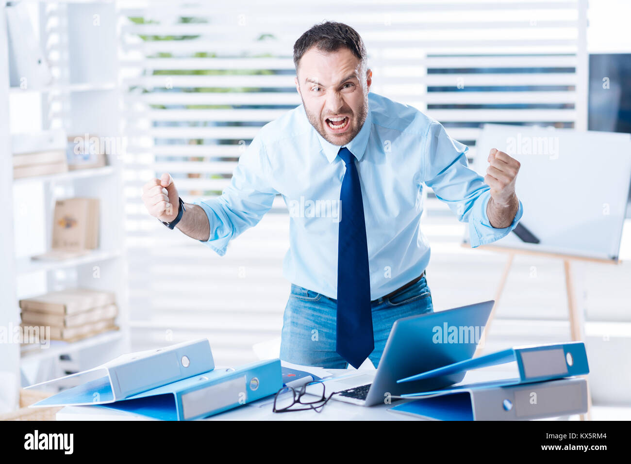 Extremely angry worker shouting and clenching his fists Stock Photo - Alamy